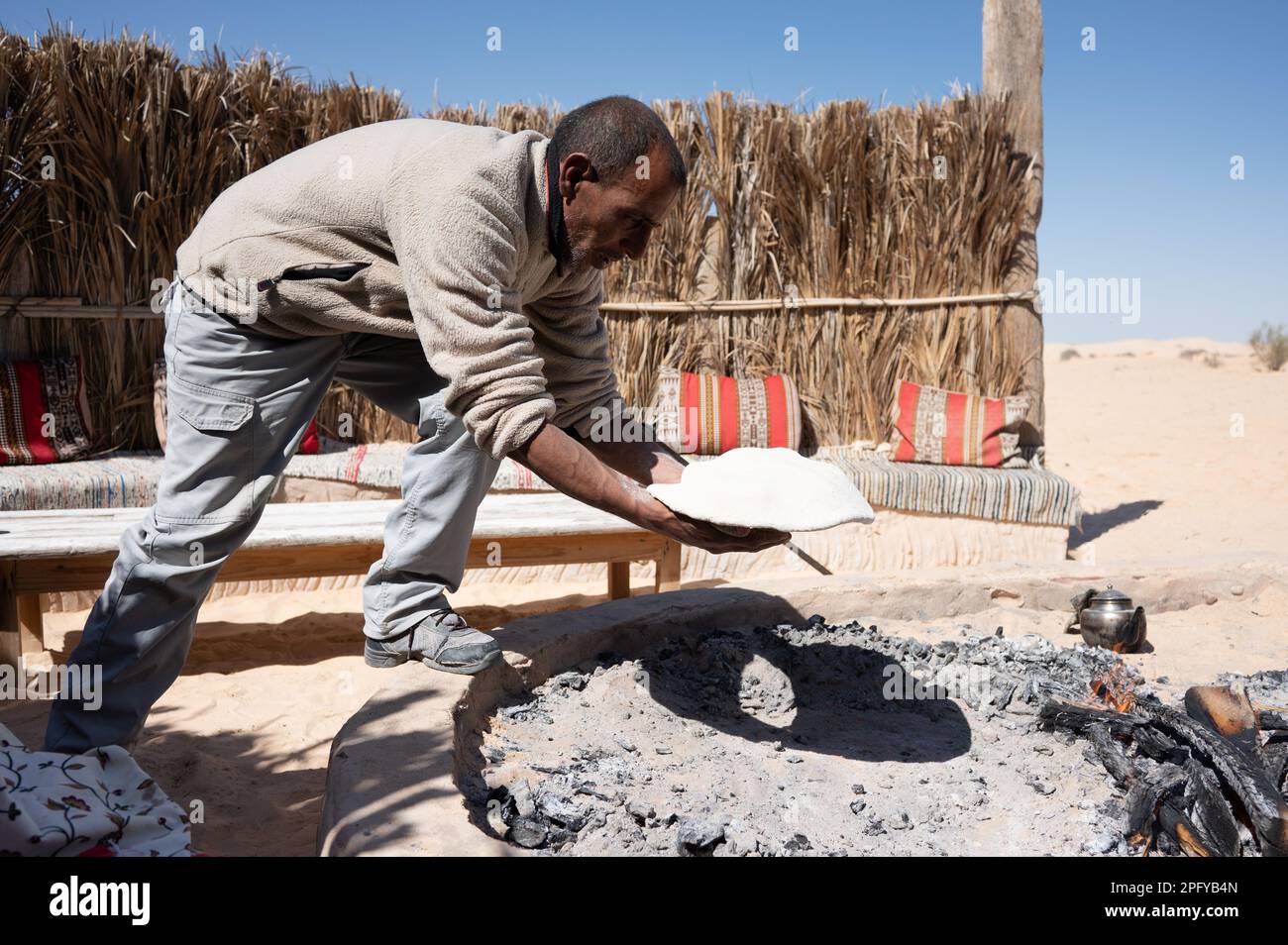 Douz, Tunisia. 03rd Mar, 2023. A man prepares ash bread on a fireplace ...
