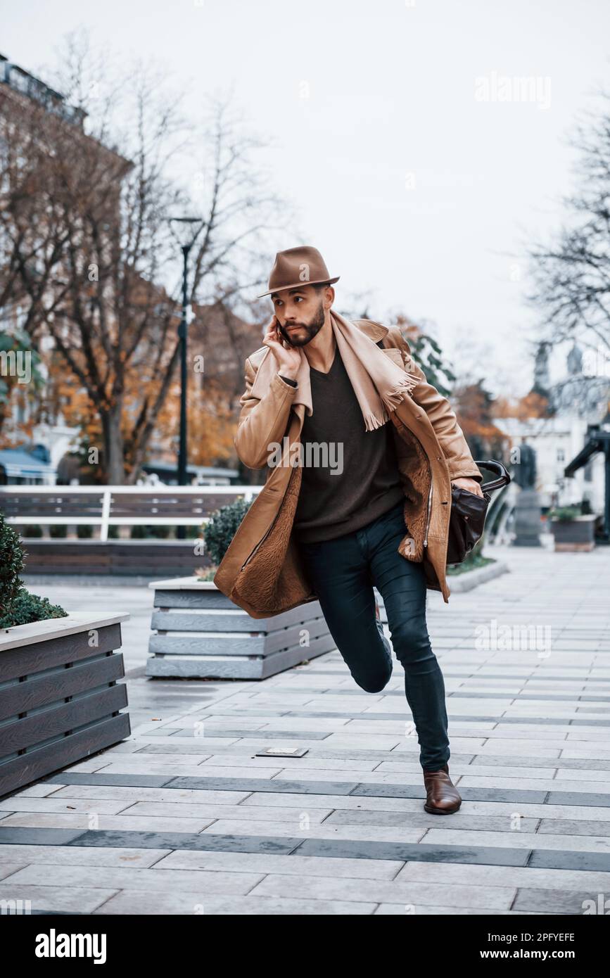 Running, late for meeting. Young male model in fashionable clothes is ...