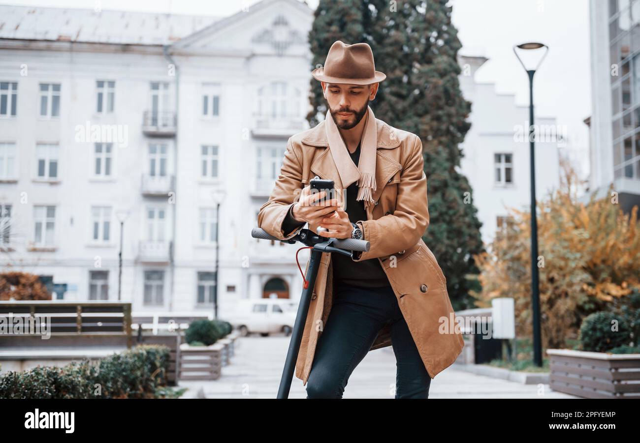 On the electric scooter. Young male model in fashionable clothes is ...