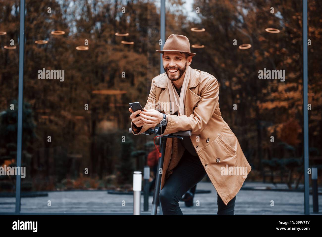 Riding electric scooter. Young male model in fashionable clothes is ...