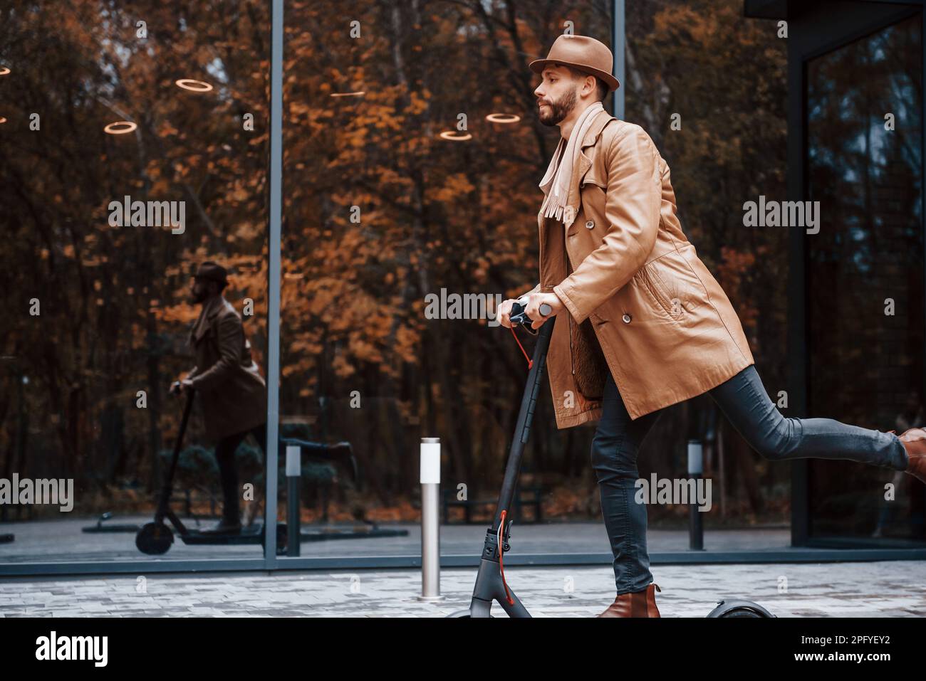 Riding electric scooter. Young male model in fashionable clothes is ...