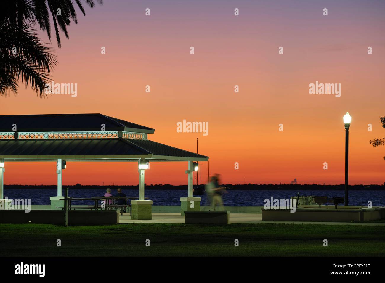 Dark silhouette of people resting under alcove roof on sea shore in ...