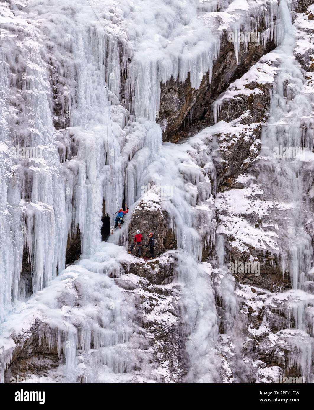 Sappada, Italy - December 30, 2022: Three climbers are climbing the icy ...