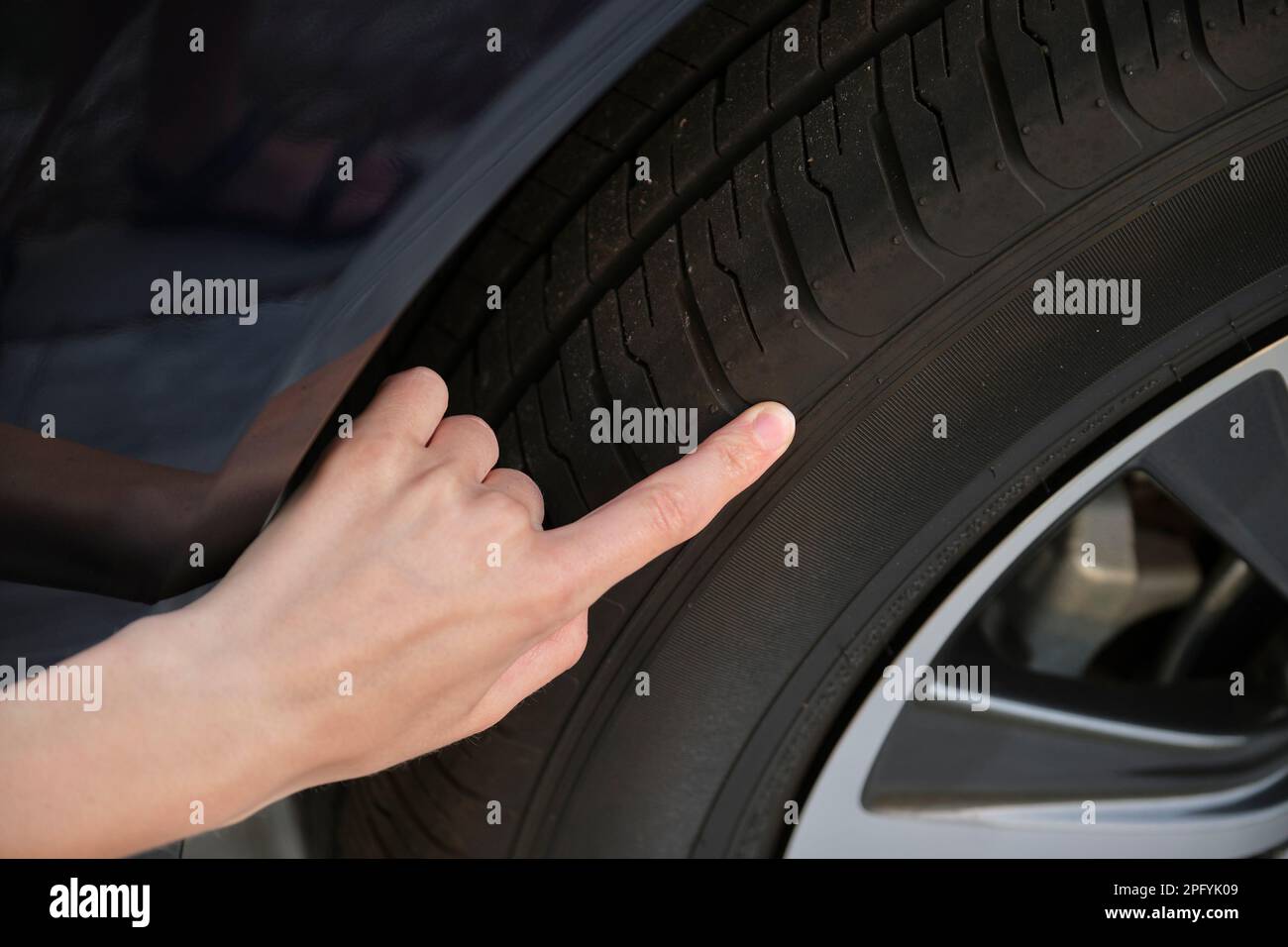 Female driver hands inspecting wheel tire of her new car. Vehicle ...
