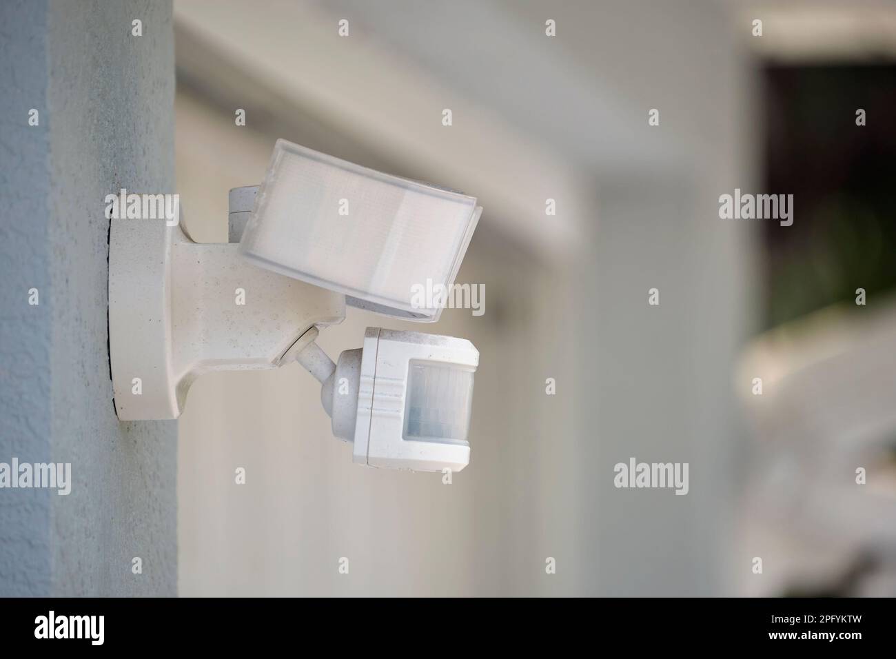 Motion sensor with light detector mounted on exterior wall of private ...