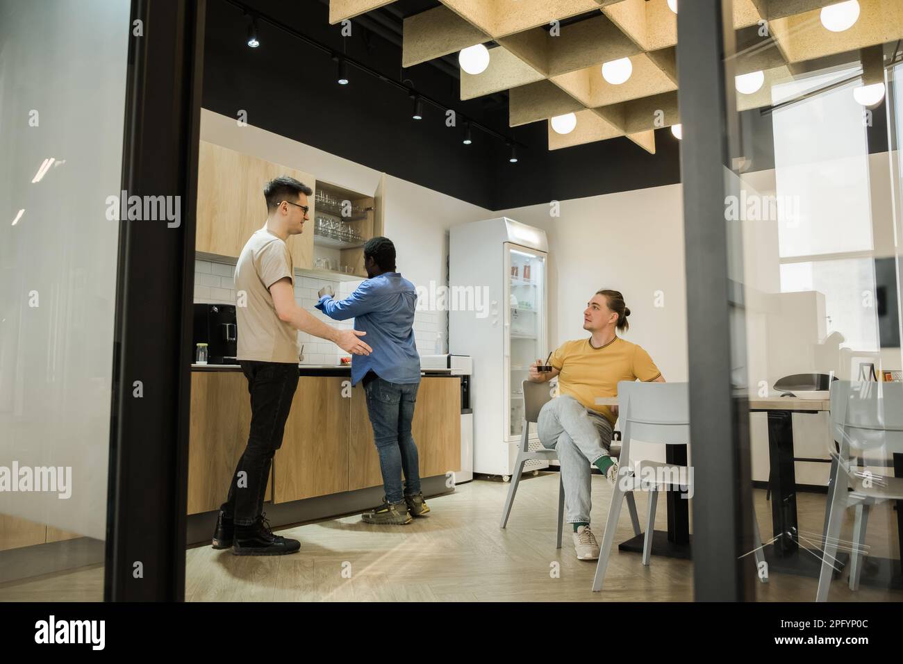 Group of cheerful young people talking and smiling during coffee break ...