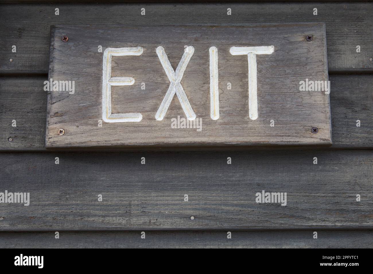 Wooden sign with white lettering that reads: EXIT. Attached to building ...