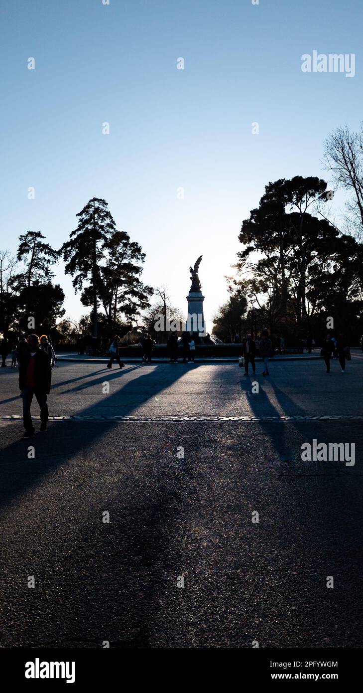 The sun sets behind a statue in a square in a park. Backlit landscape ...