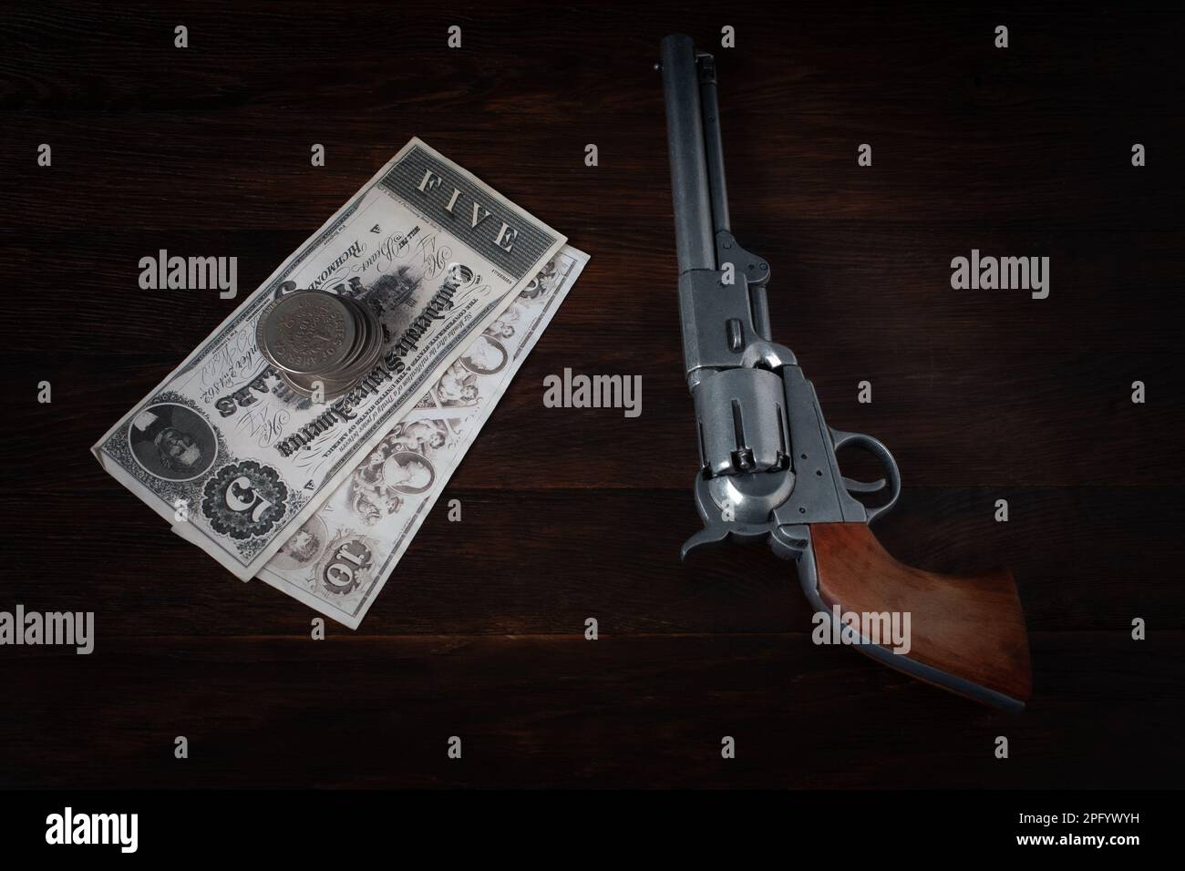 Old west revolver with bill and silver dollars on wooden table Stock ...