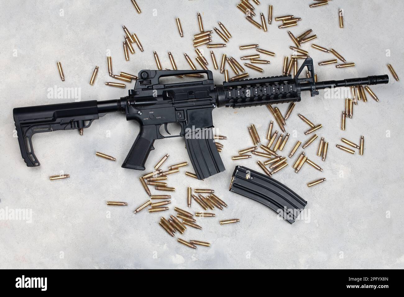 M4 carbine and 5.56mm shells and magazine with bullets on grey concrete ...