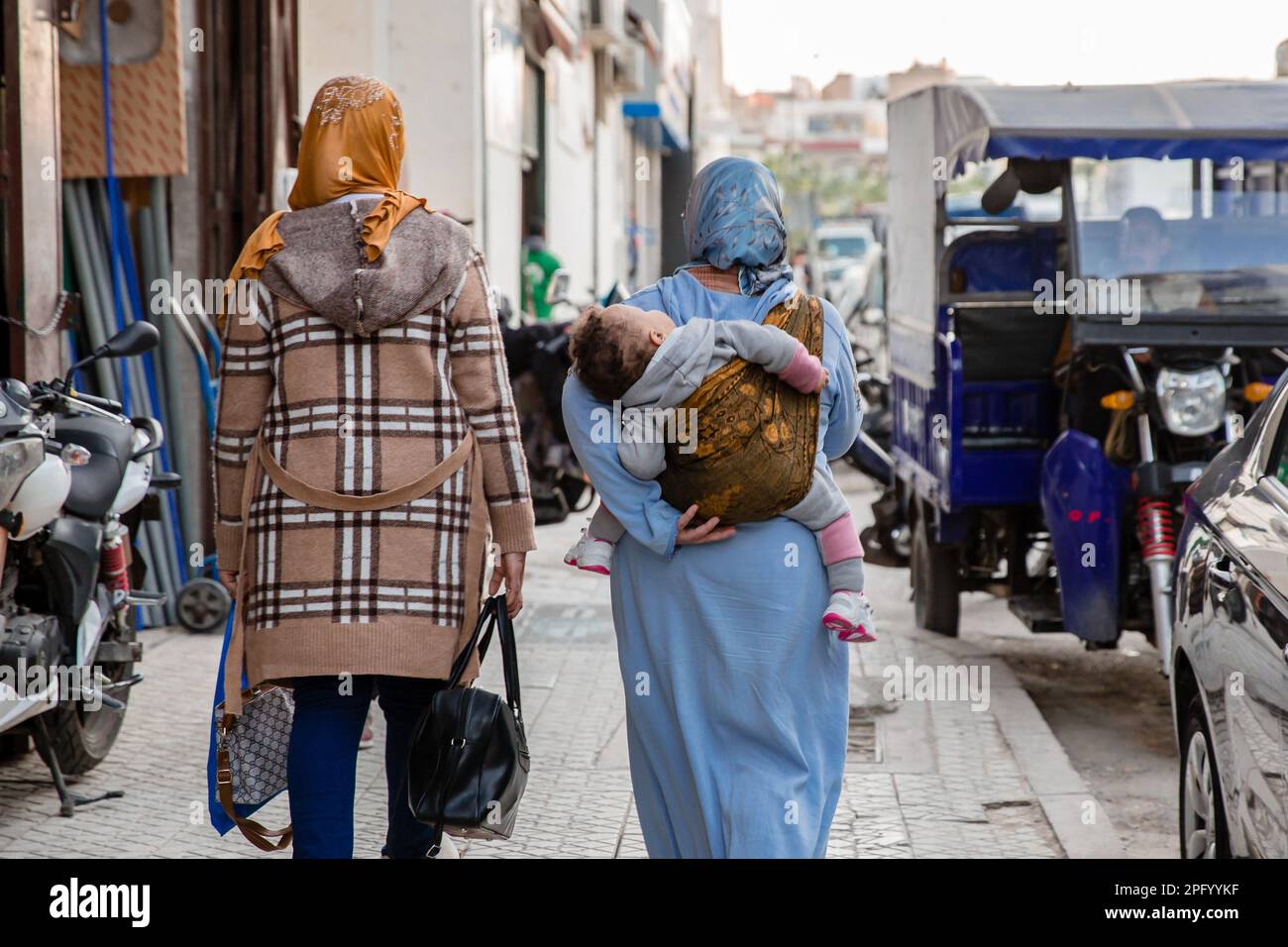 Two women walking down the street with a baby in Fes Stock Photo - Alamy
