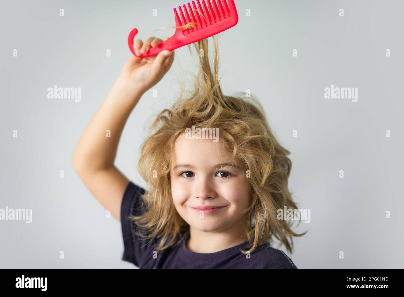 Funny kids hairstyle. Child with tangled blonde long hair tries to comb ...