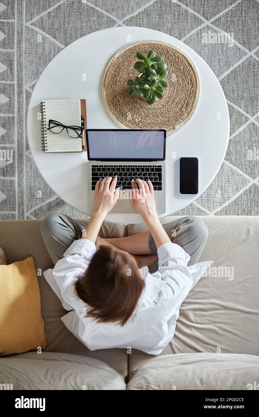 Mockup white screen laptop woman using computer sitting on sofa at home ...
