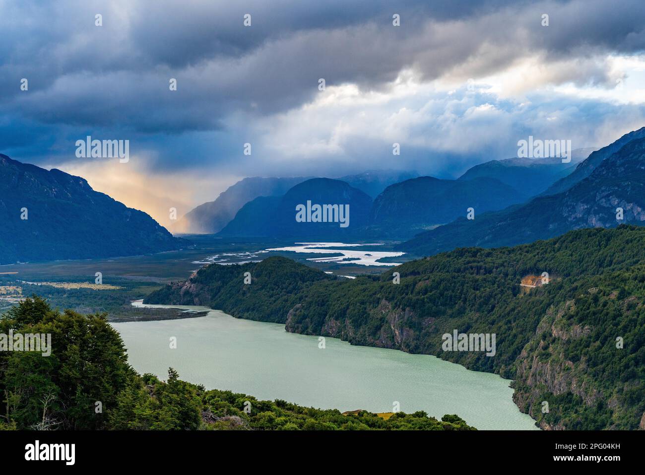 Rays of sunshine break through the rain clouds over the river valley of ...
