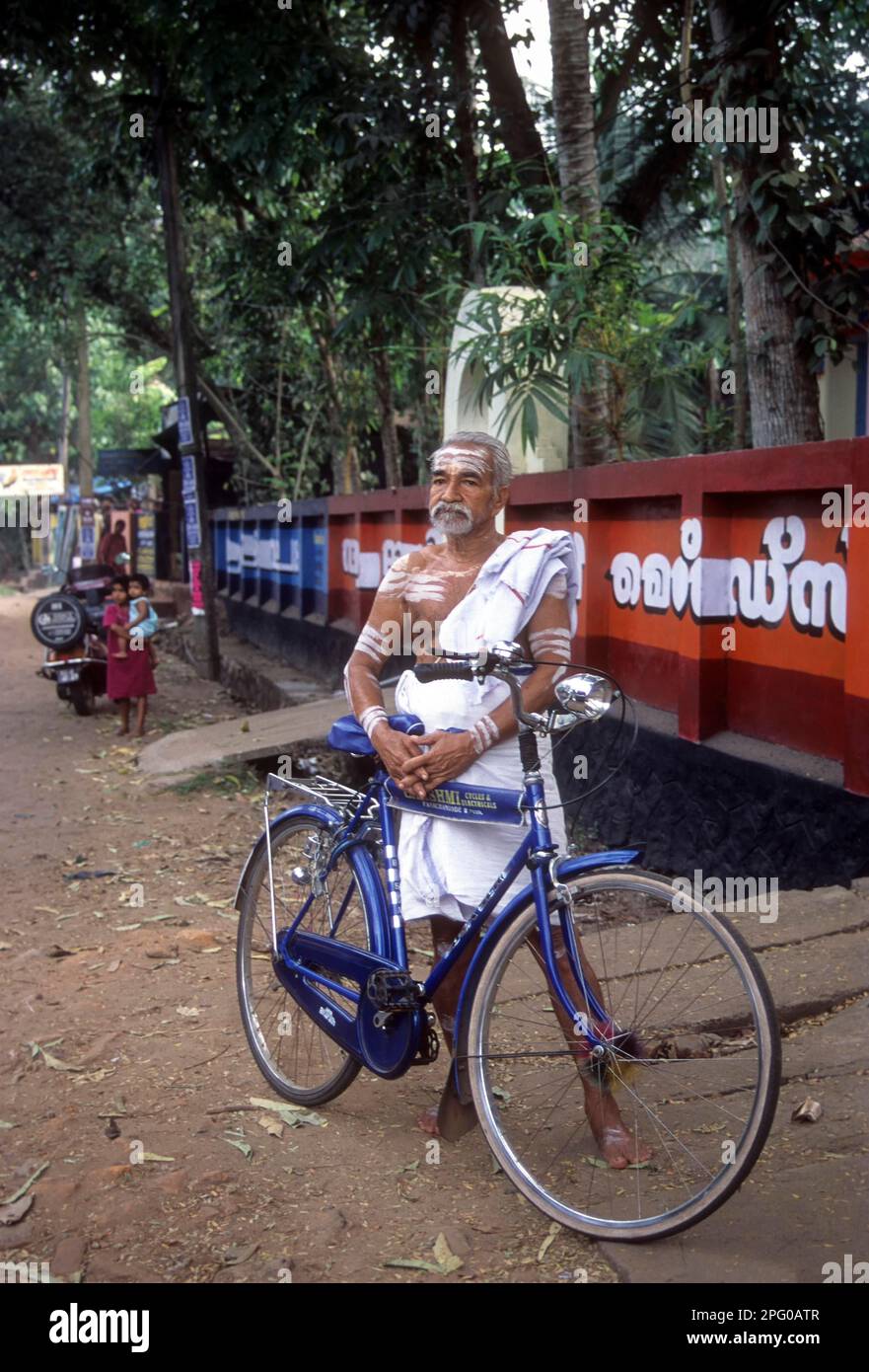 A Priest applying holy ash on body standing with bicycle, Kerala, India ...
