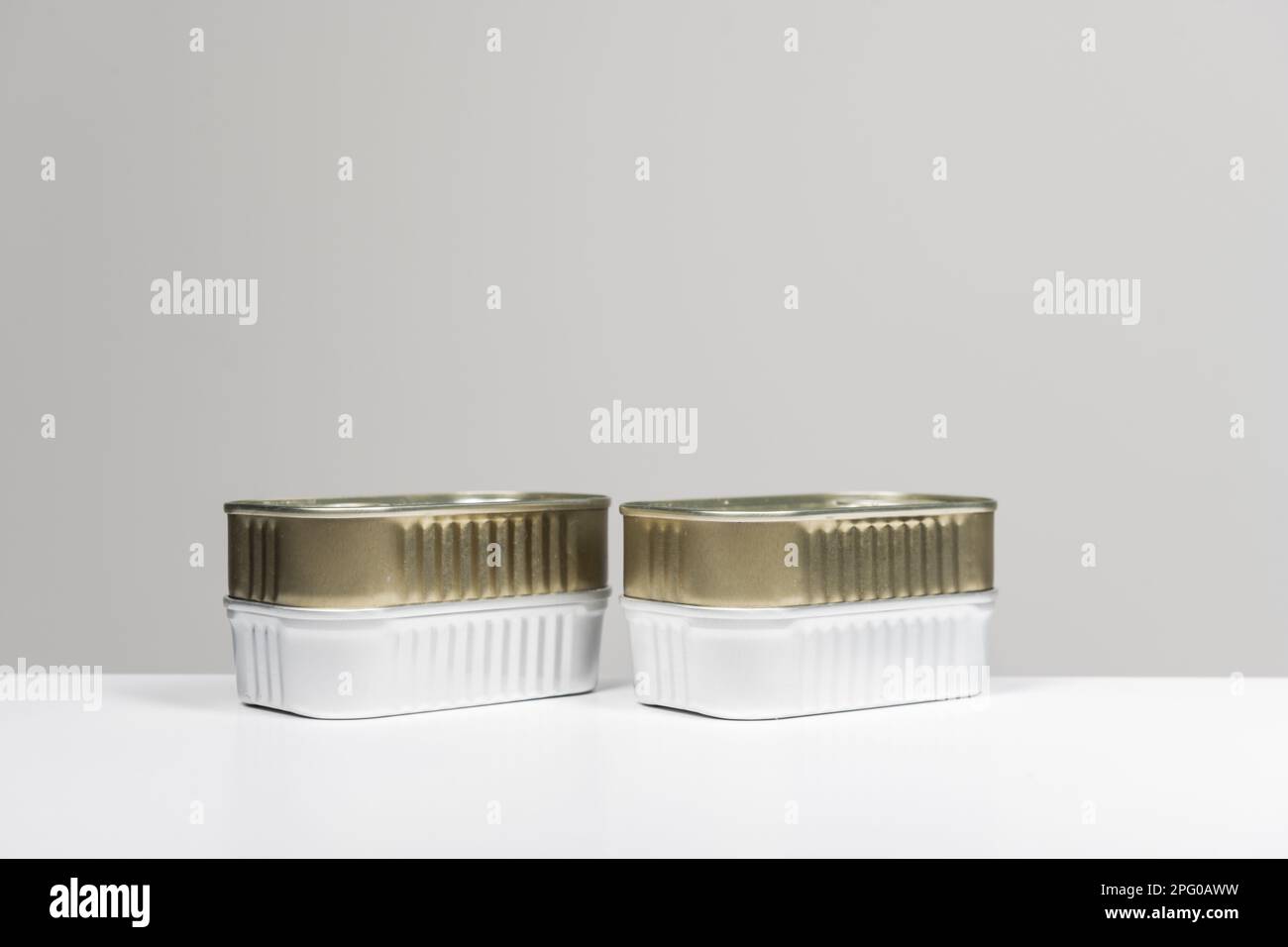 Metal canned fish cans of different types on a smooth white surface ...