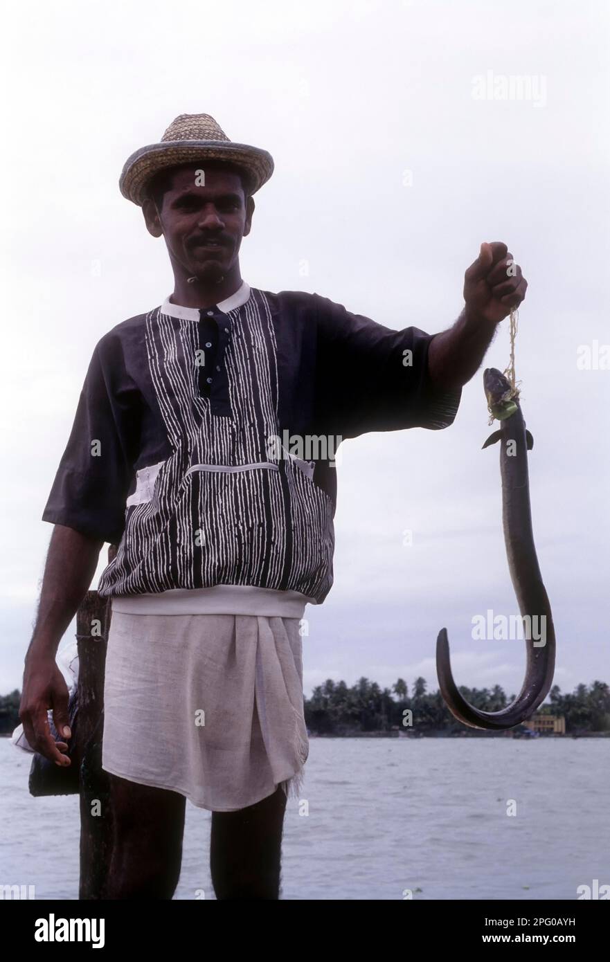 A (Anguilliformes) fisherman caught Eel fish and standing on the floor ...