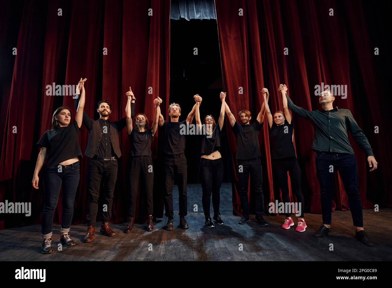 People bowing to audience. Group of actors in dark colored clothes on ...
