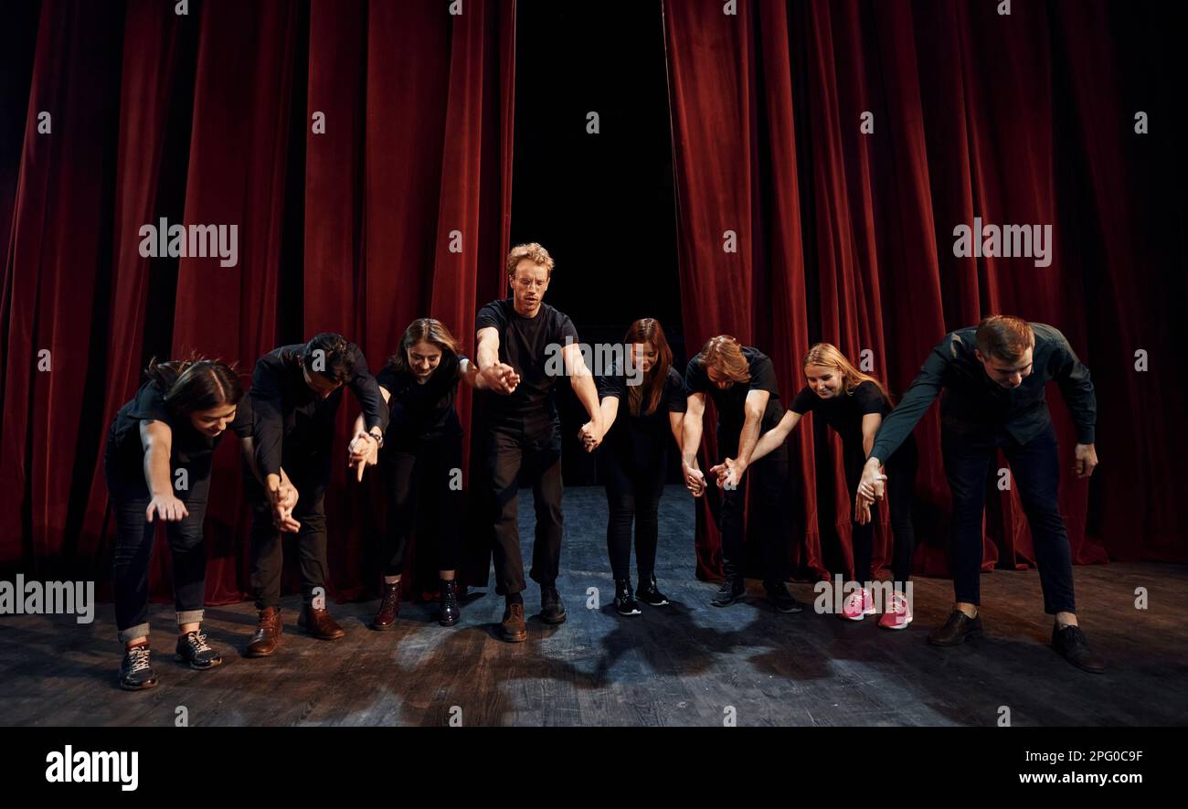 People bowing to audience. Group of actors in dark colored clothes on ...