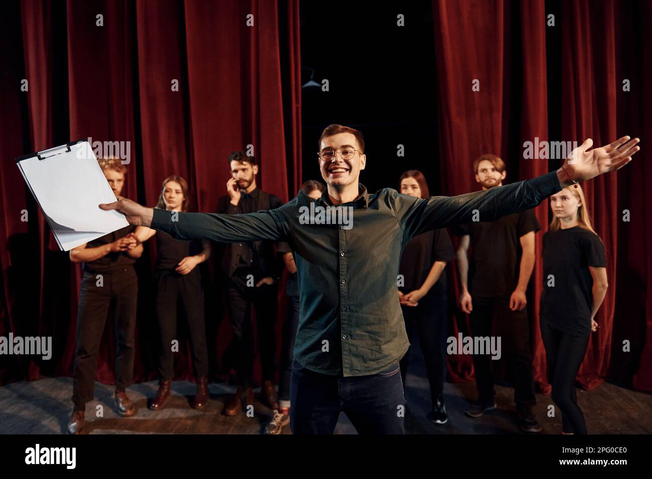 Man is practicing his role. Group of actors in dark colored clothes on ...