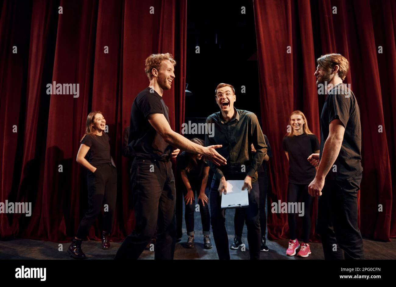 Working together. Group of actors in dark colored clothes on rehearsal ...
