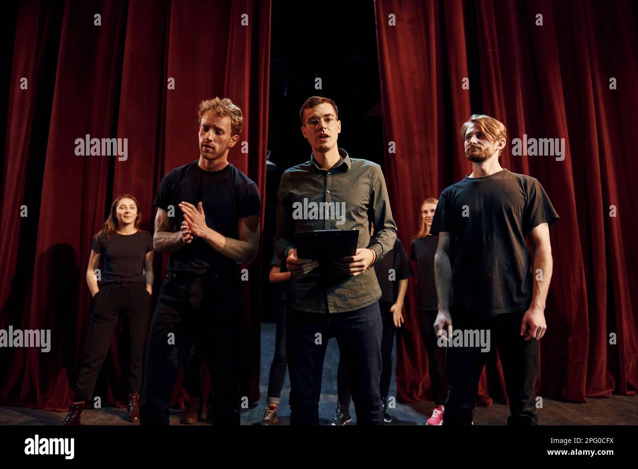 Working together. Group of actors in dark colored clothes on rehearsal ...