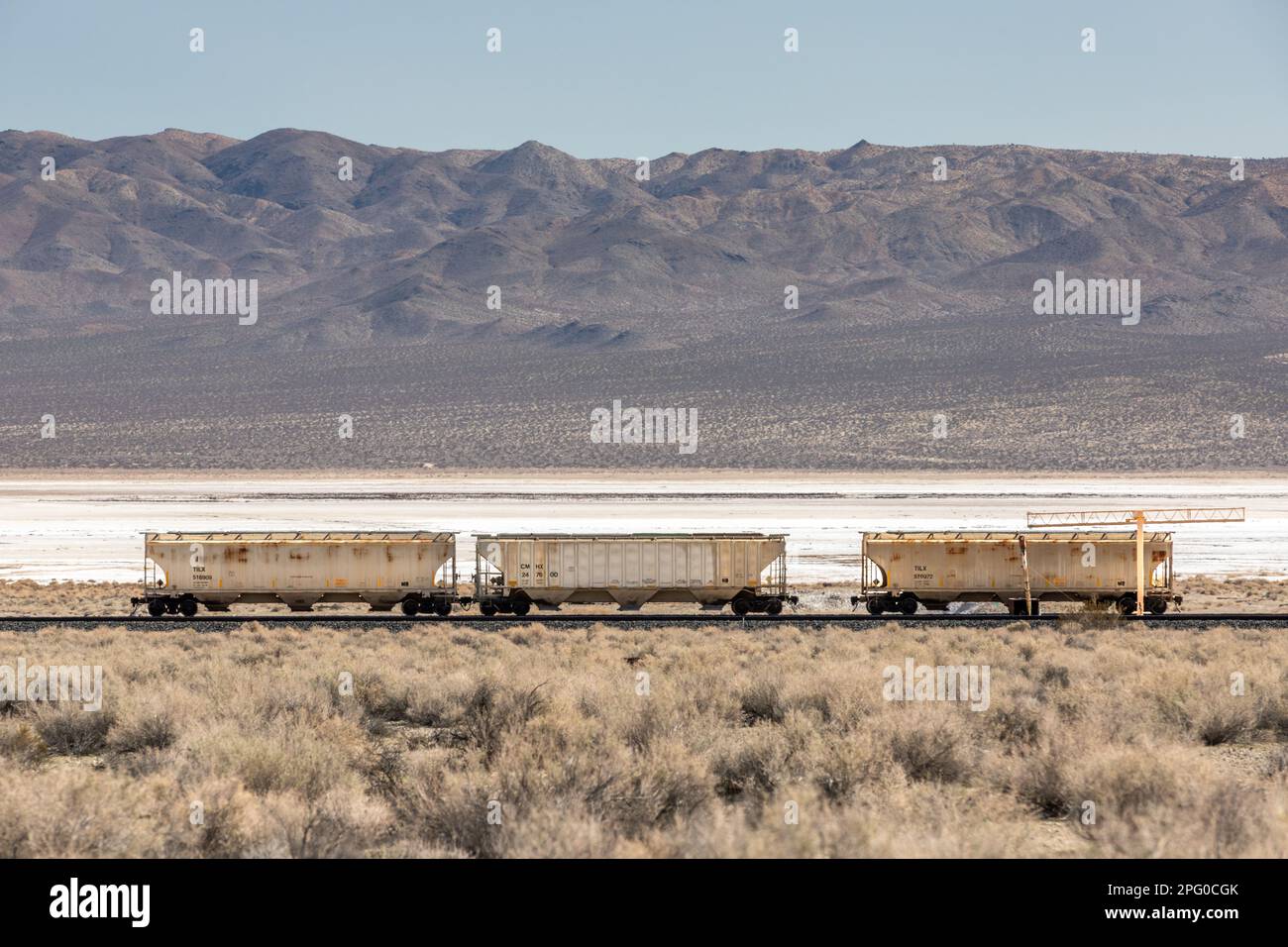 Three rail cars on tracks behind them dry desert lake in the Mojave ...