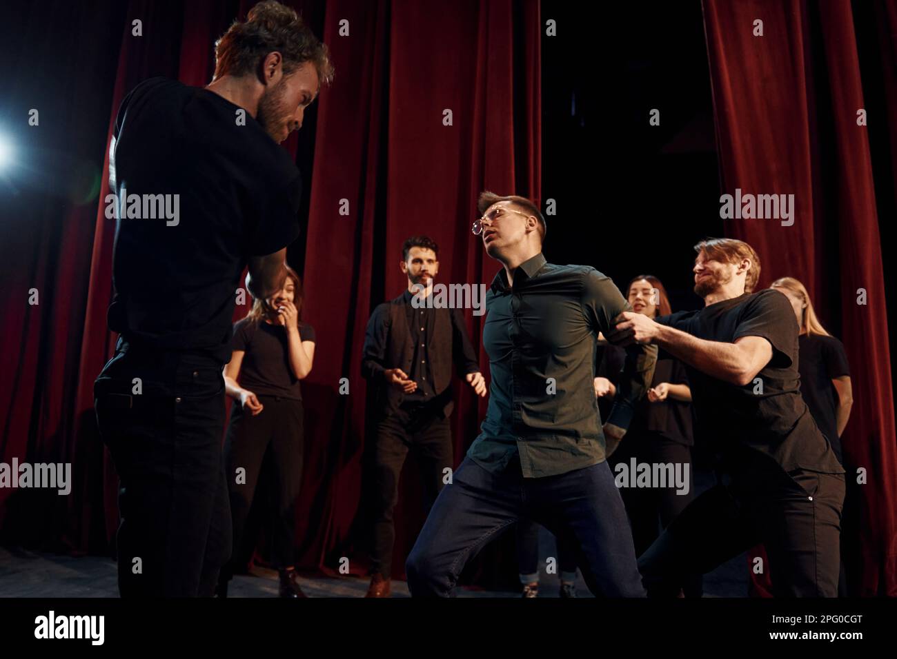 Fight scene. Group of actors in dark colored clothes on rehearsal in ...