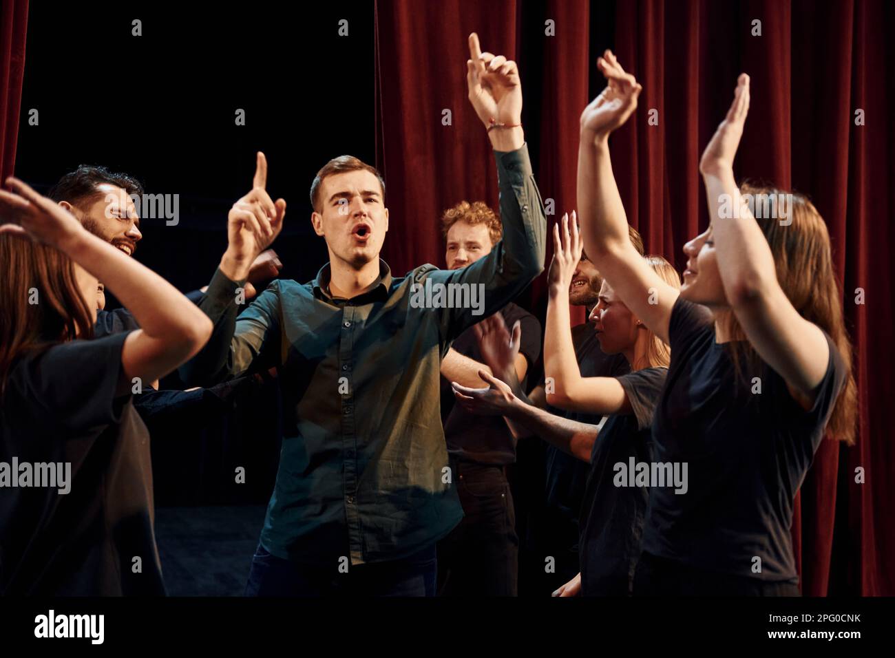 Giving high five, celebrating success. Group of actors in dark colored ...