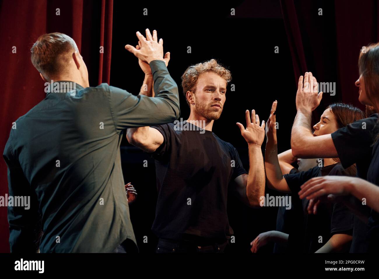 Giving high five, celebrating success. Group of actors in dark colored ...