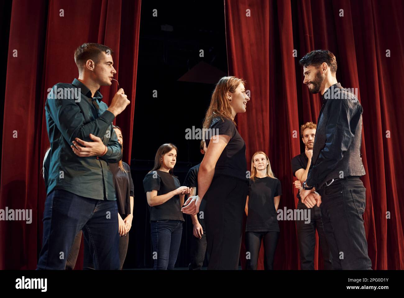 Two people talking. Group of actors in dark colored clothes on ...