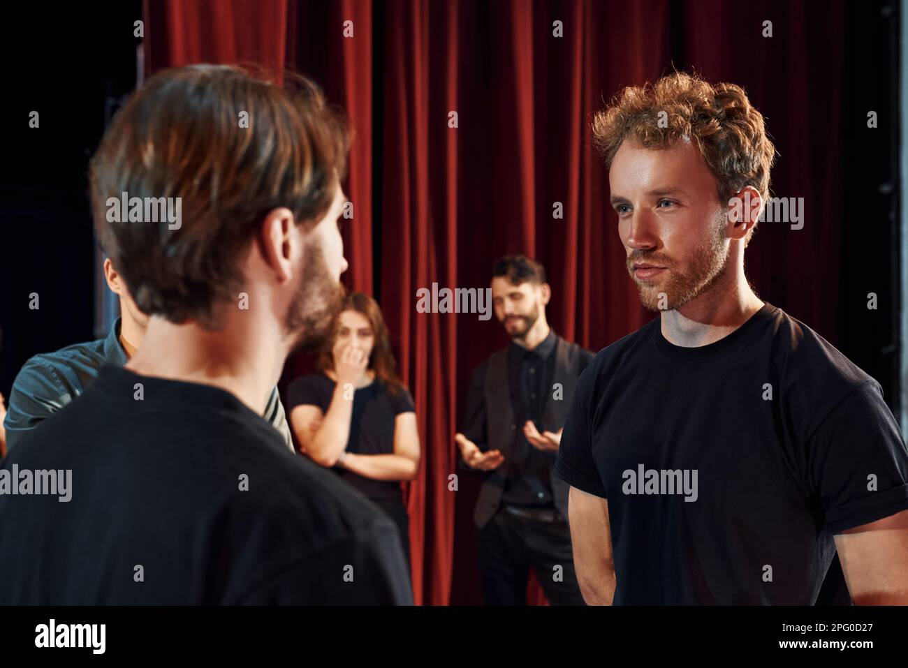 Two people talking. Group of actors in dark colored clothes on ...