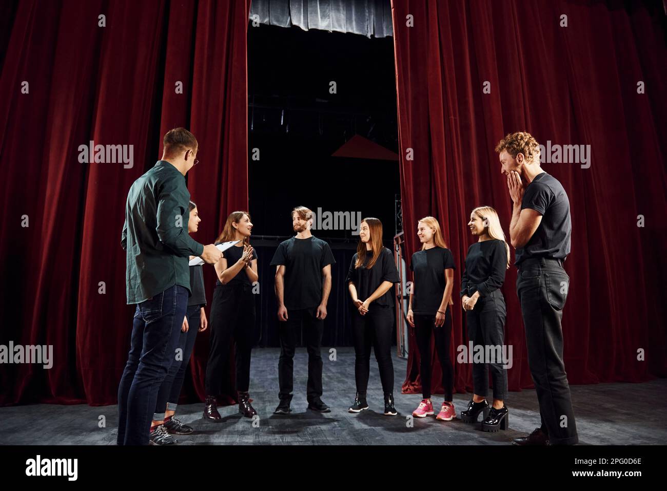 Working together. Group of actors in dark colored clothes on rehearsal ...