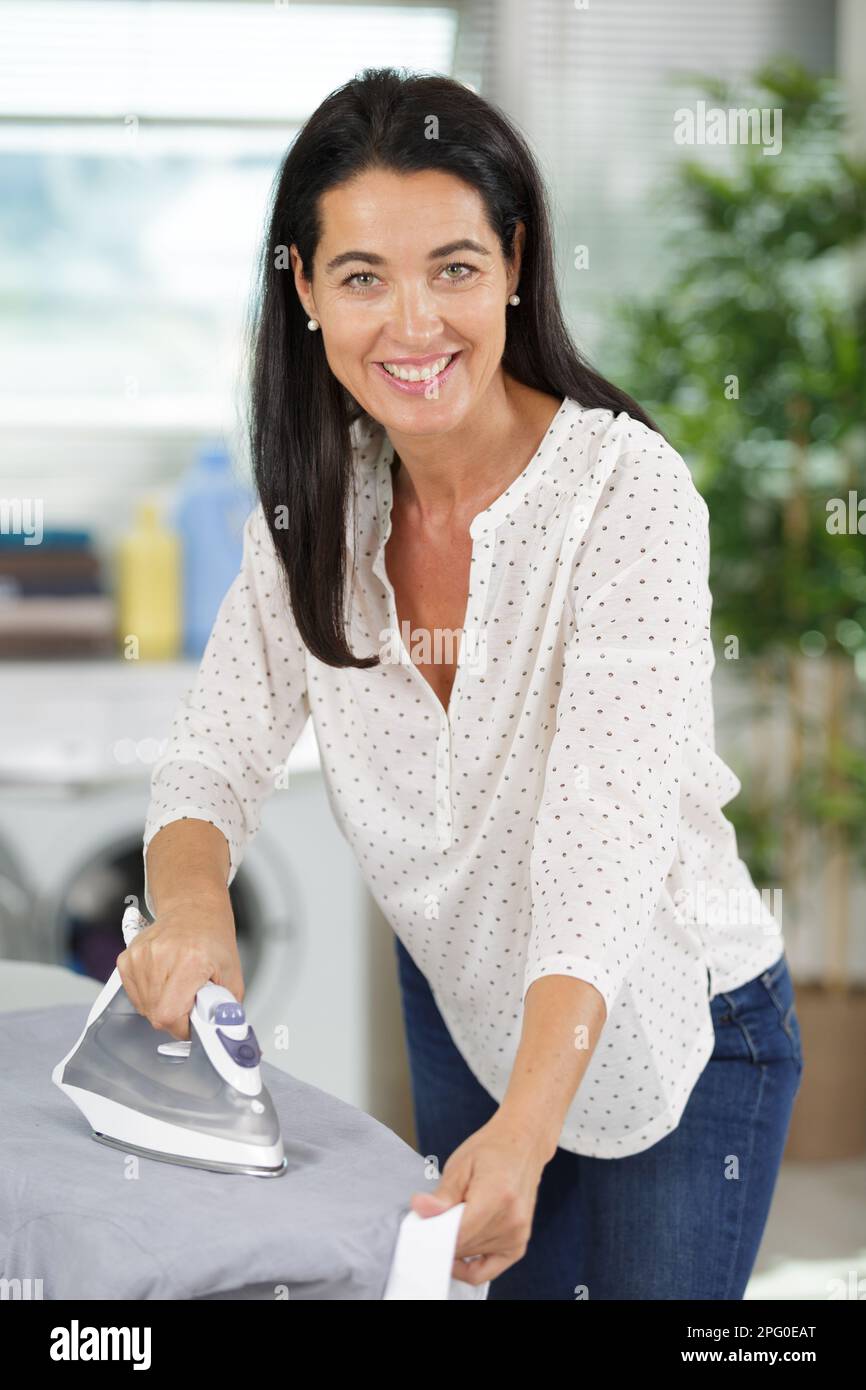 middle aged woman uses iron at home Stock Photo - Alamy