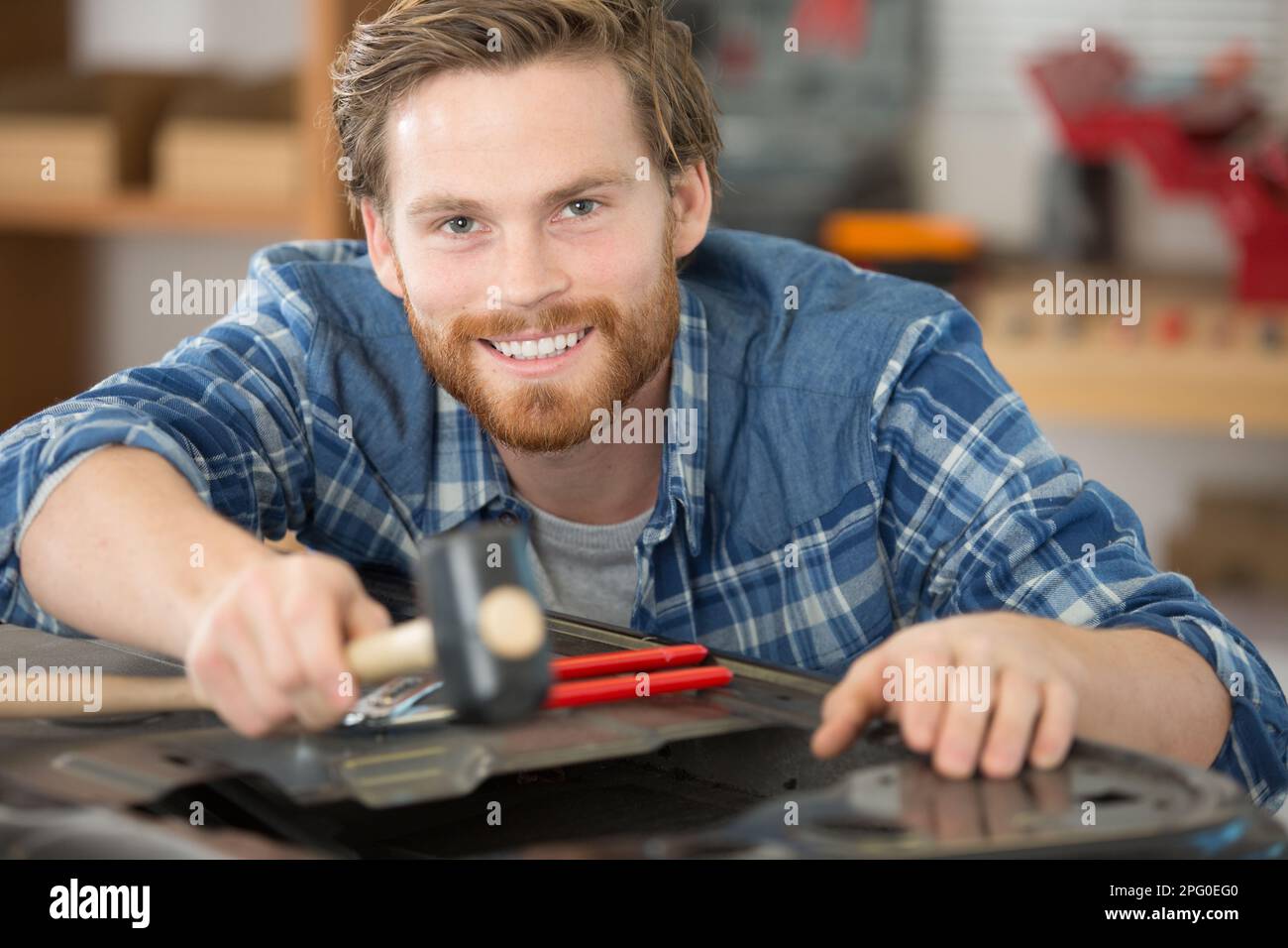 a smiling happy bearded man with a hammer Stock Photo - Alamy