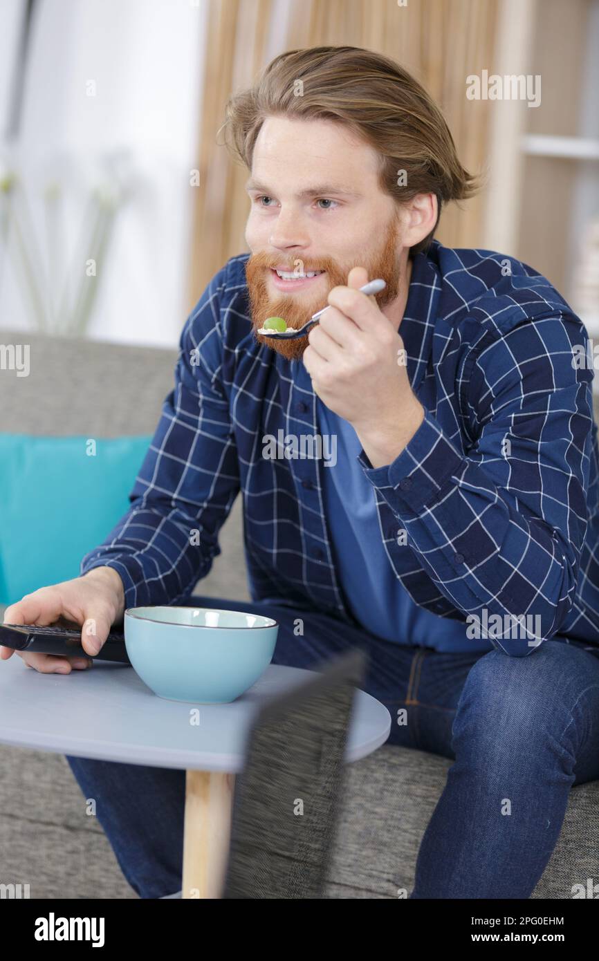 Man eating cereal watching tv hi-res stock photography and images - Alamy