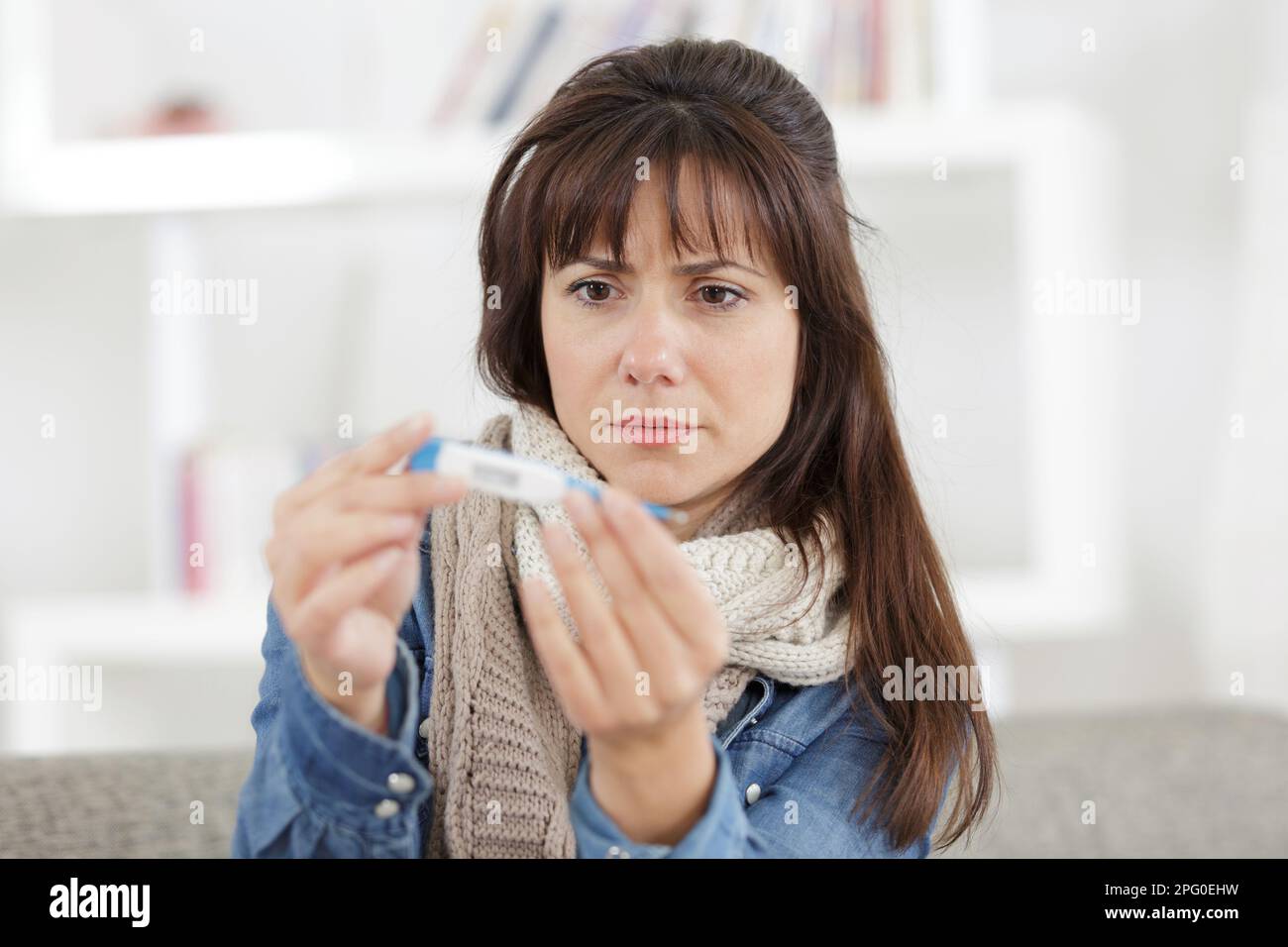 sad woman with a thermometer in her hand Stock Photo - Alamy