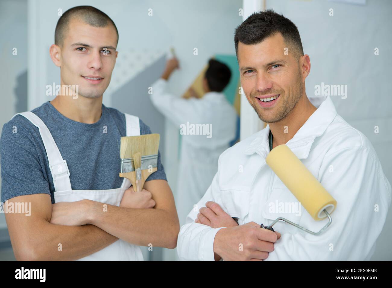 portrait of two male decorators holding roller and brushes Stock Photo ...