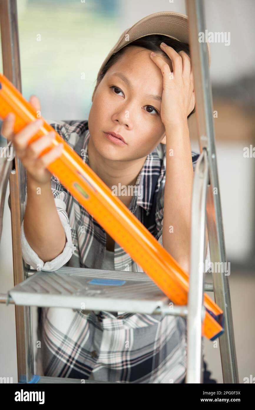 confused engineer girl holding the water level ruler Stock Photo - Alamy