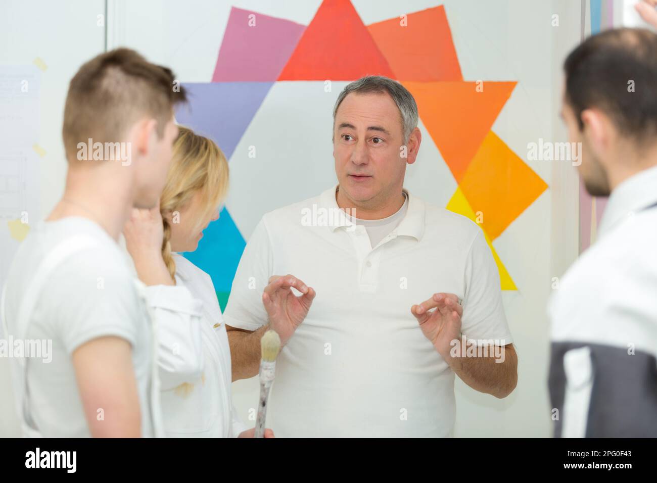 instructor showing apprentices how to paint Stock Photo - Alamy