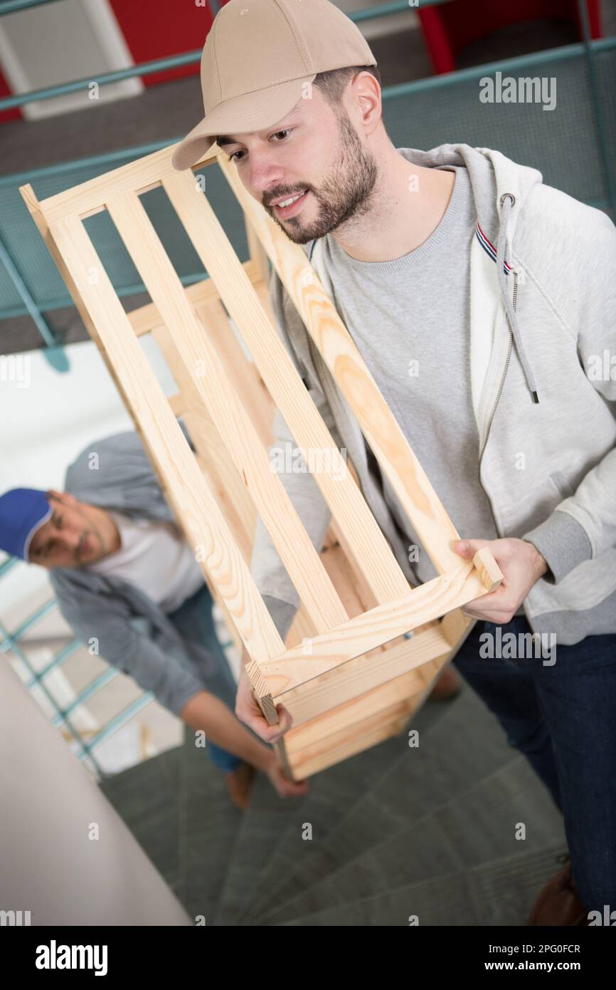 two men carrying wooden shelf Stock Photo - Alamy