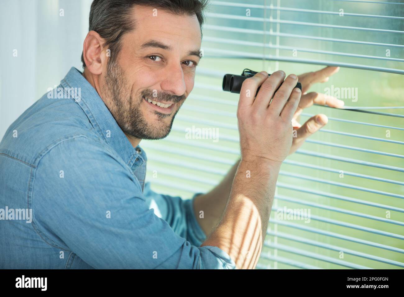 excited man spying through the window blinds with binoculars Stock ...