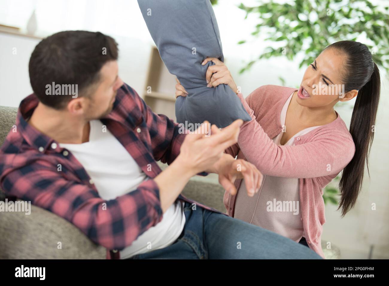 angry woman hitting man with a cushion Stock Photo - Alamy