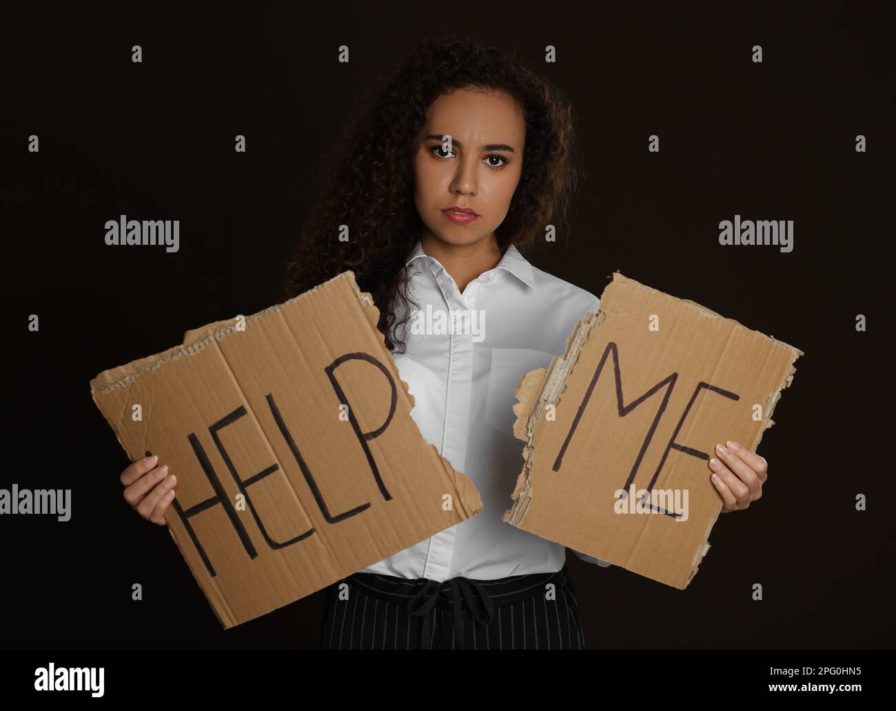 Unhappy African American woman with HELP ME sign on dark background ...