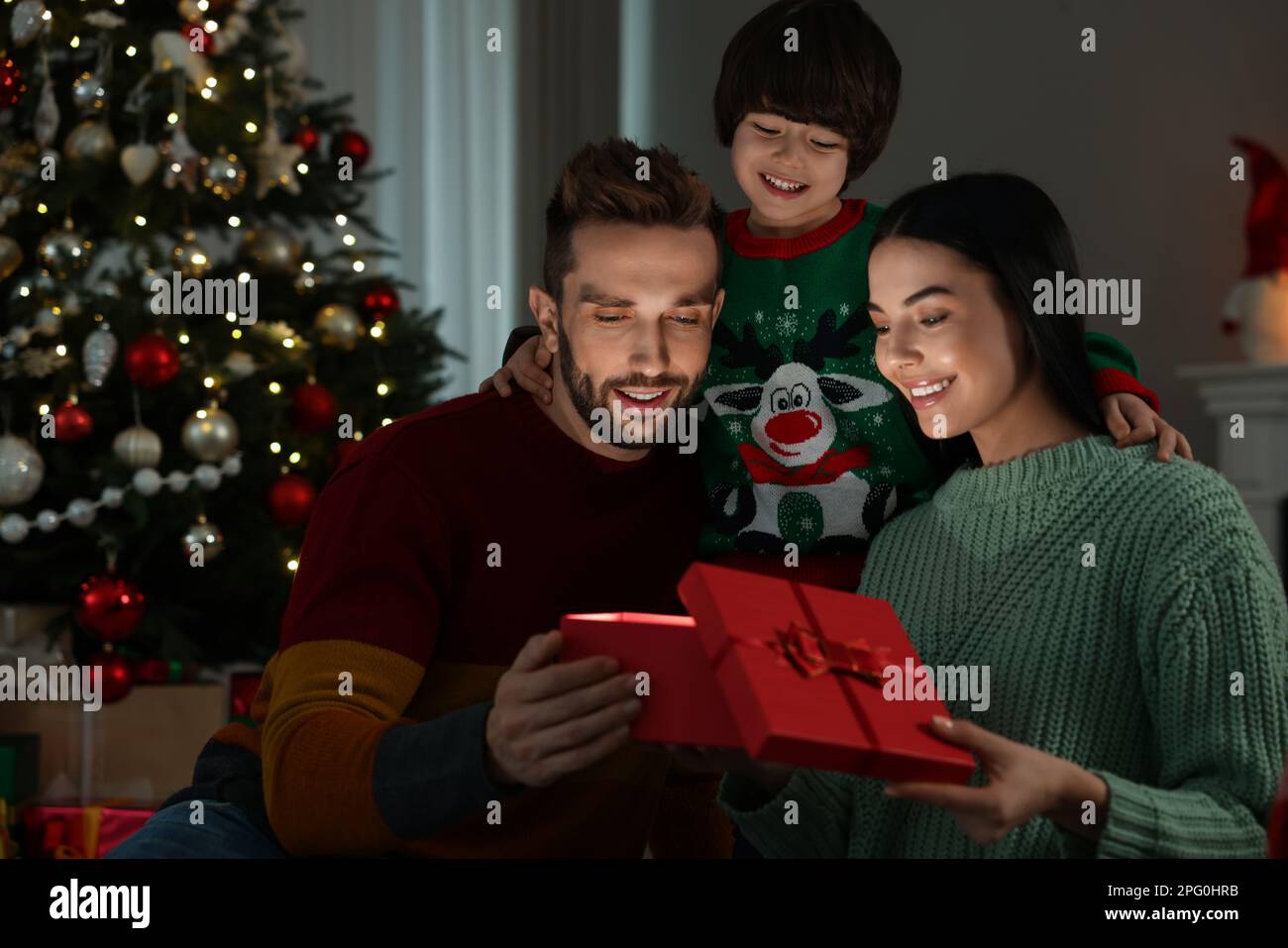 Happy family opening gift box with magical light at home. Christmas ...