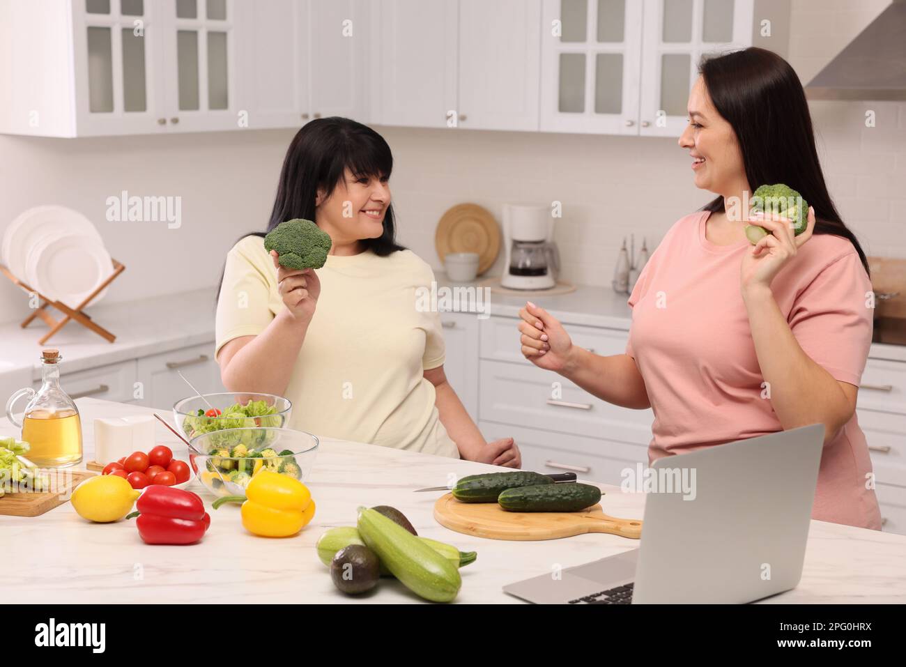 Happy overweight women having fun while cooking together in kitchen ...