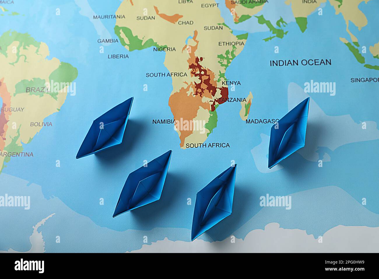 Light blue paper boats on world map, flat lay Stock Photo - Alamy
