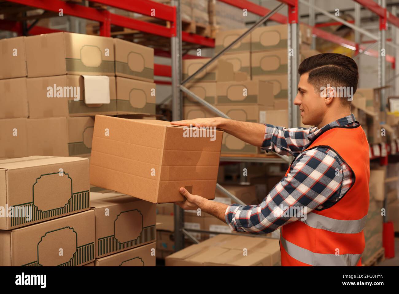 Worker stacking cardboard boxes in warehouse. Wholesaling Stock Photo ...