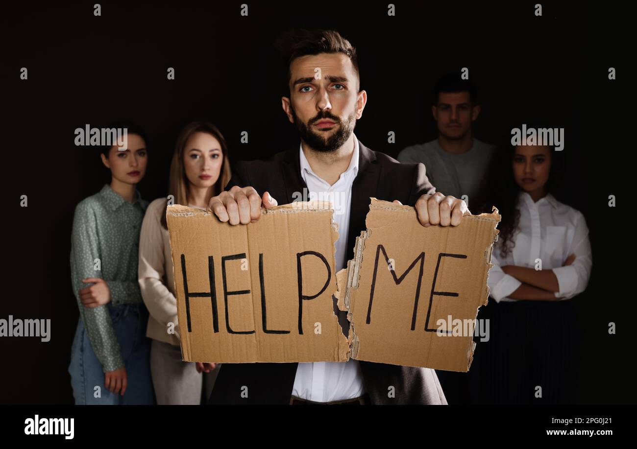 Unhappy man with HELP ME sign and group of people behind his back on ...