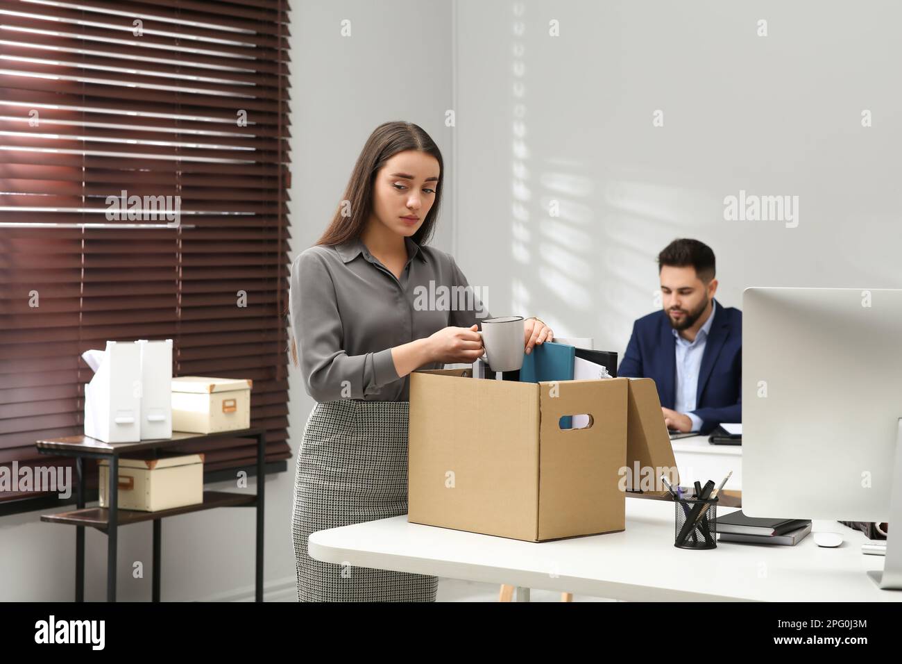 Dismissed woman packing personal stuff into box in office Stock Photo ...